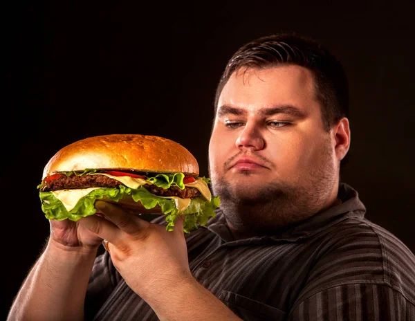 Fat man eating fast food hamberger. Breakfast for overweight person ...