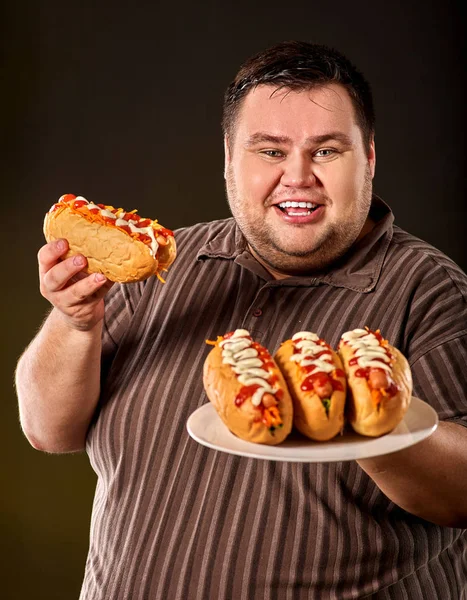 Fat man eating fast food hot dog. Breakfast for overweight person ...