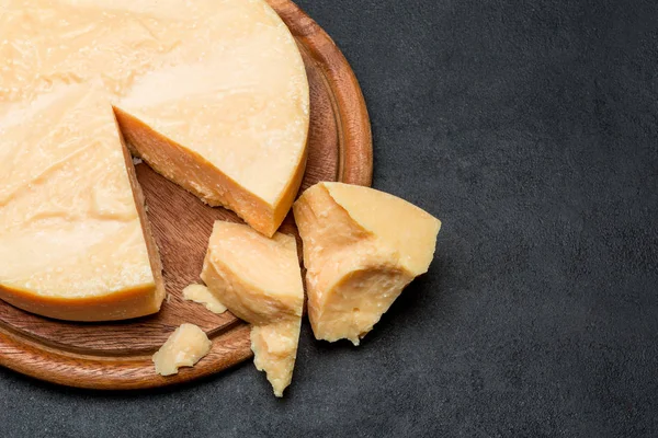 Head of parmesan or parmigiano hard cheese and pieces on concrete ...