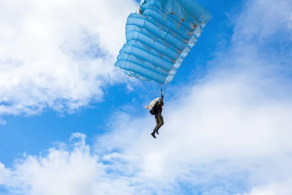 Single military parachute jumper on a blue wing parachute on blu ...