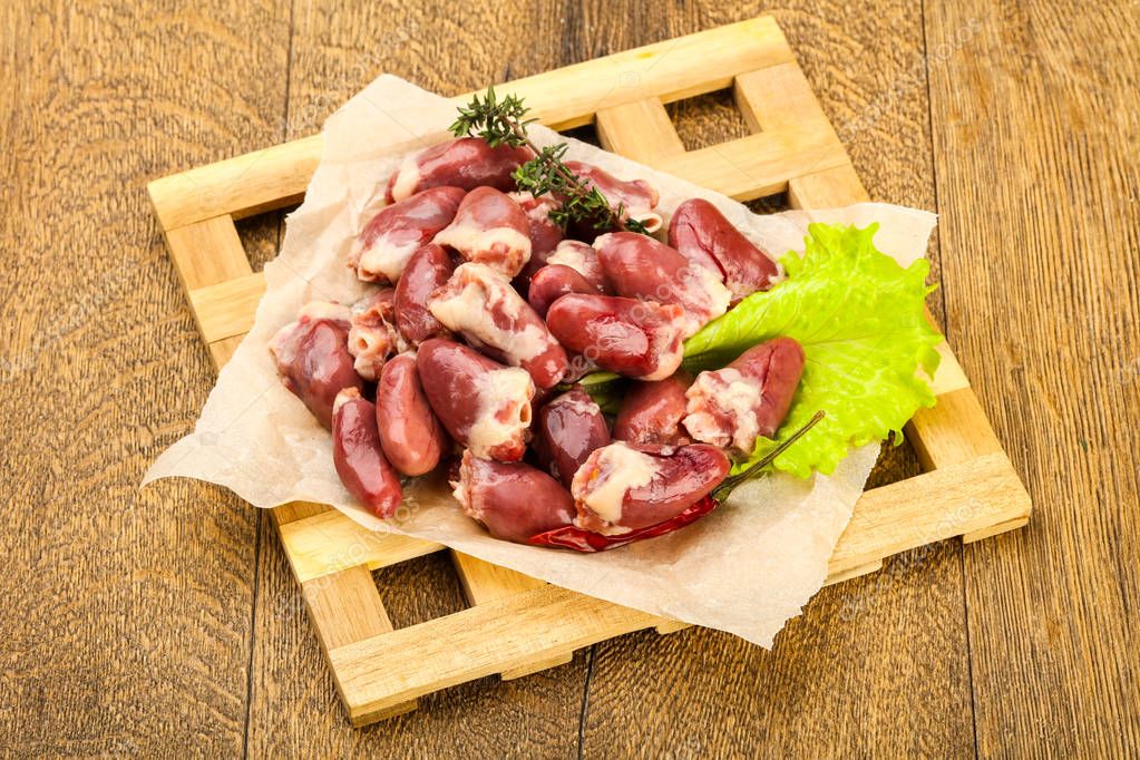 Corazones de pollo crudos amontonados con rama de tomillo 2023