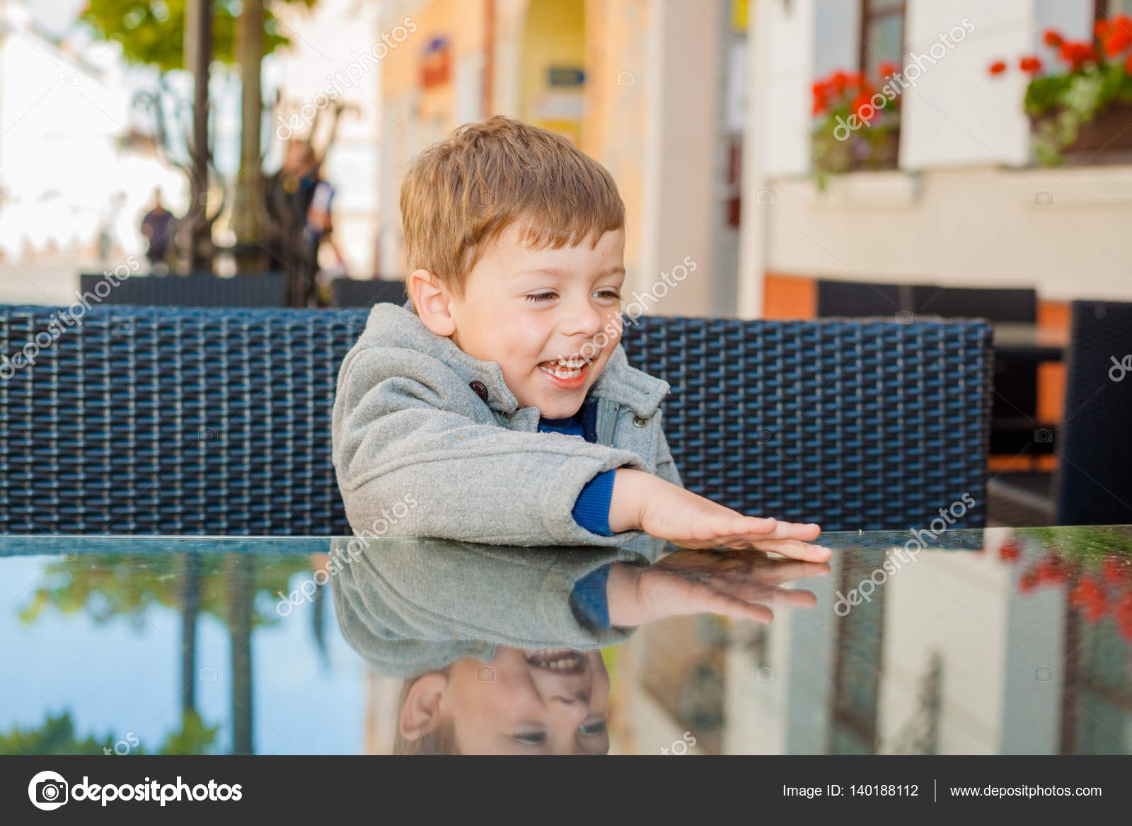 Emotional boy at a table in a cafe Stock Photo by ©RumisPhoto 140188112