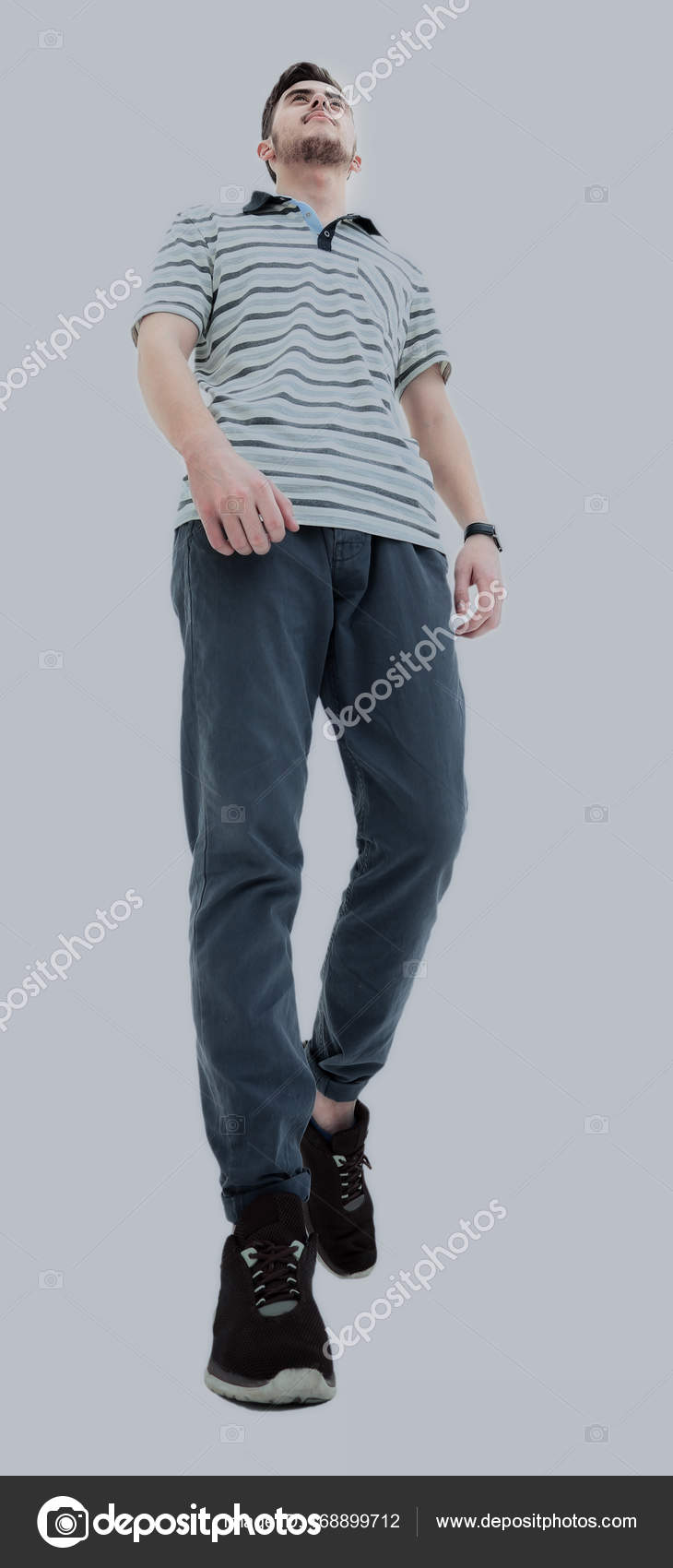Bottom view of a smiling young casual man walking, on a white ba ...