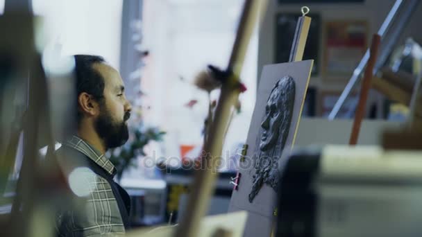 Sculptor creating sculpture of humans face on canvas while young woman ...