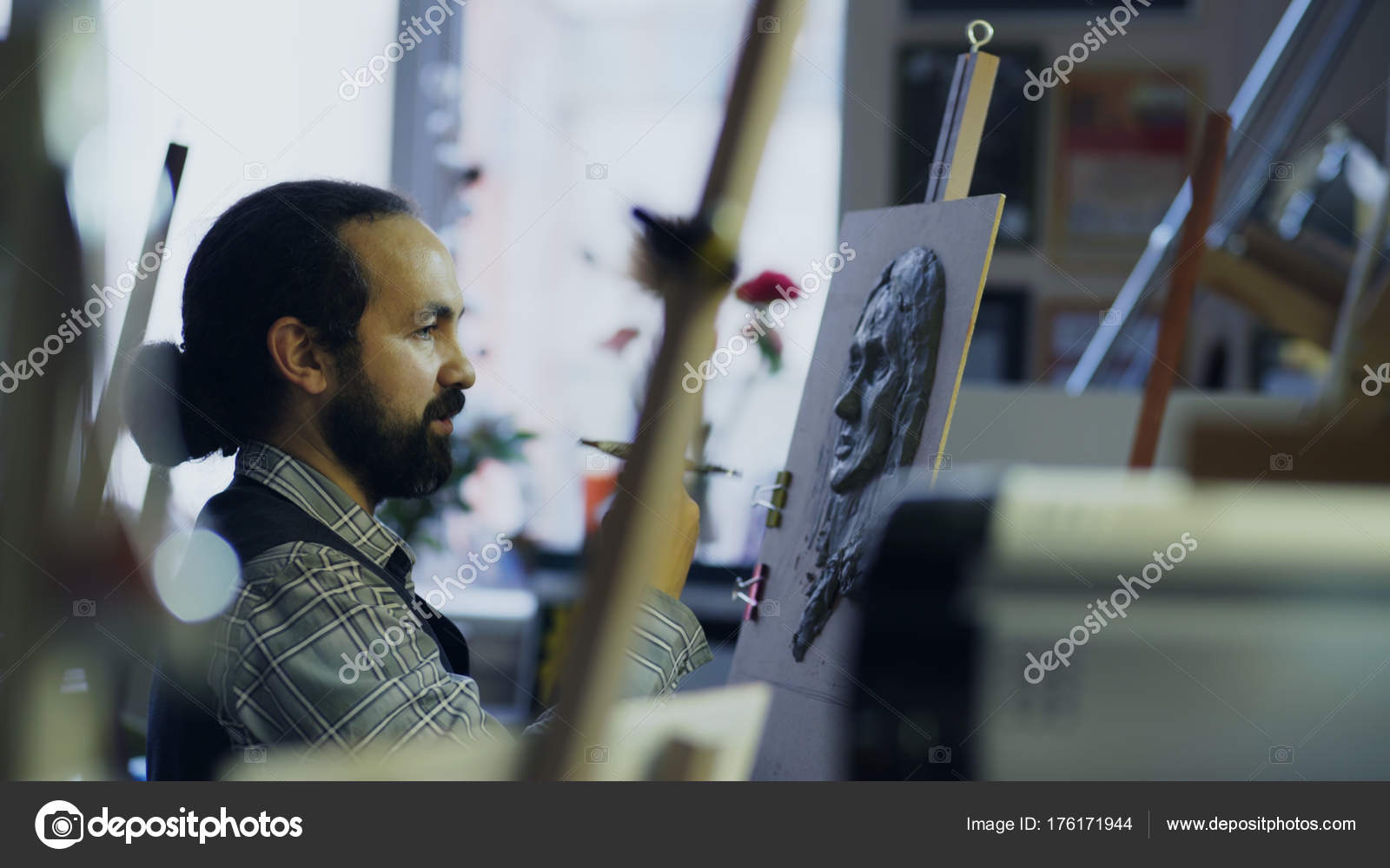 Sculptor creating sculpture of humans face on canvas while talking with ...