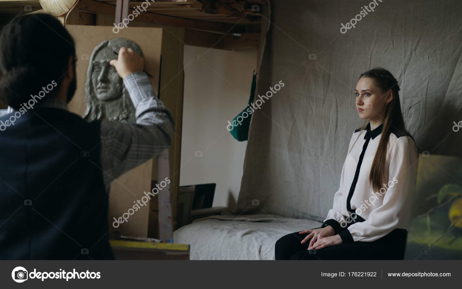 Sculptor creating sculpture of humans face on canvas while young woman ...