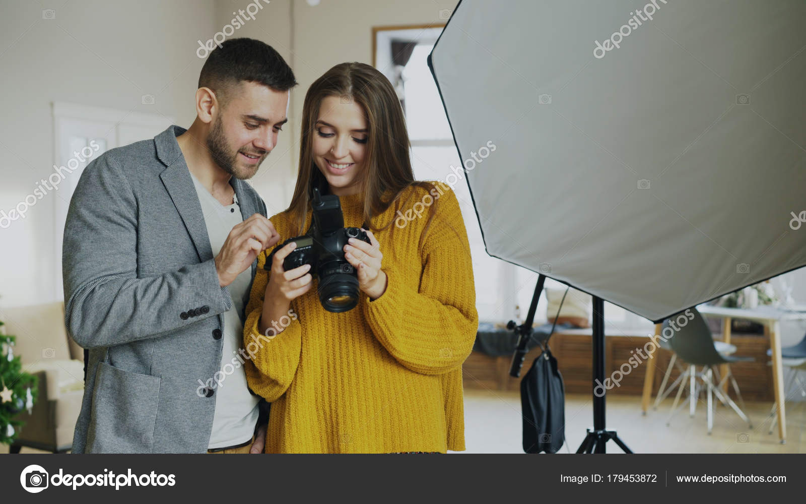 Fotógrafo profesional hombre mostrando fotos en cámara digital a hermosa modelo chica en estudio ...