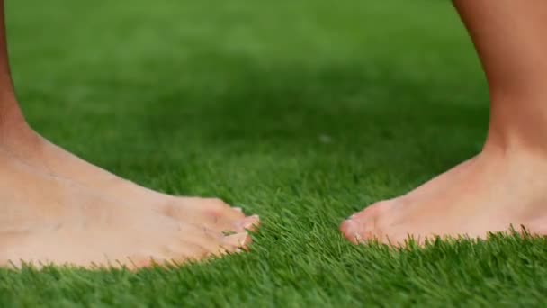 Two barefoot people on the green grass. Step on each others foot ...