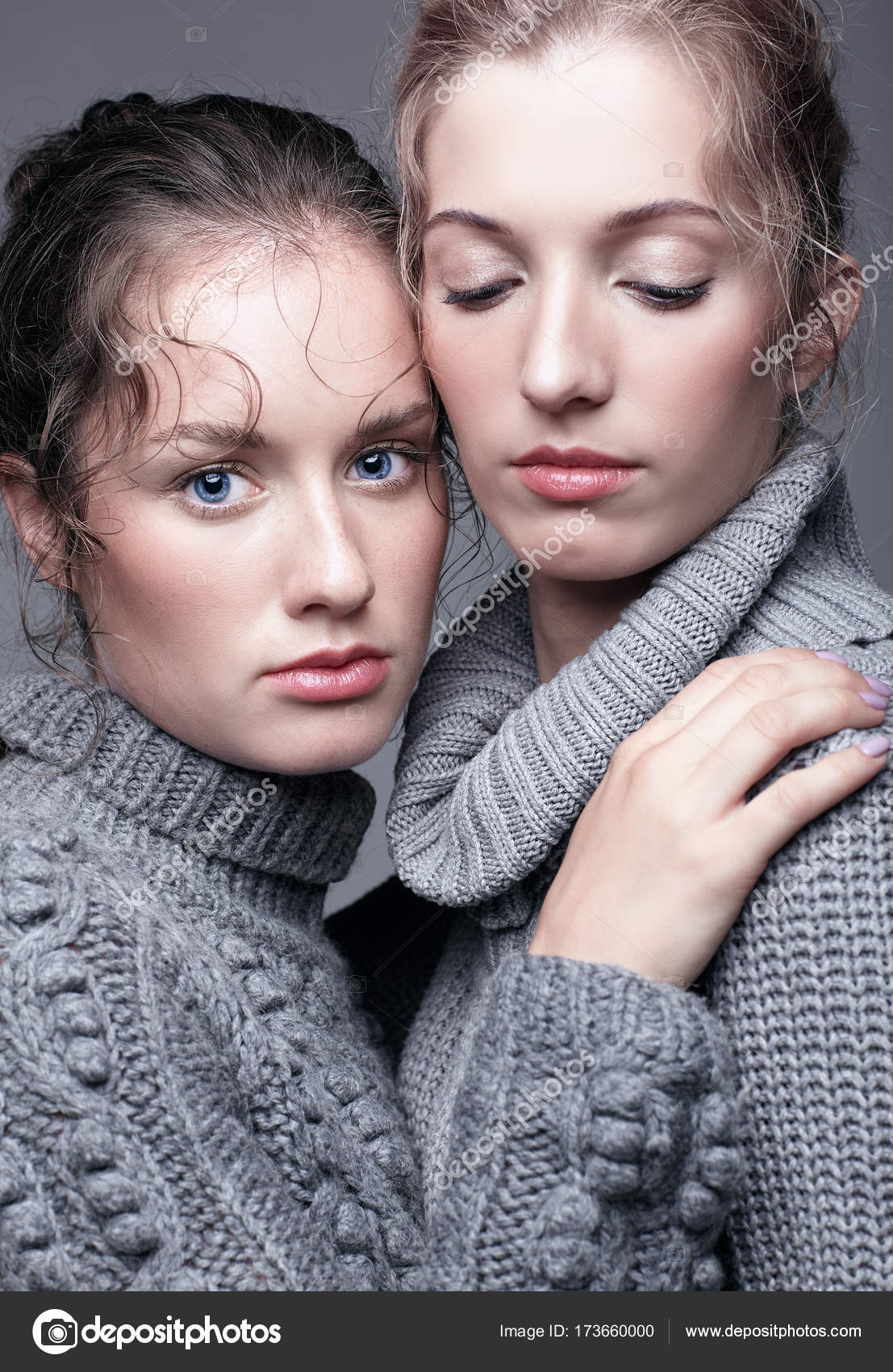 Two young women in gray sweaters on grey background. Beautiful g Stock ...