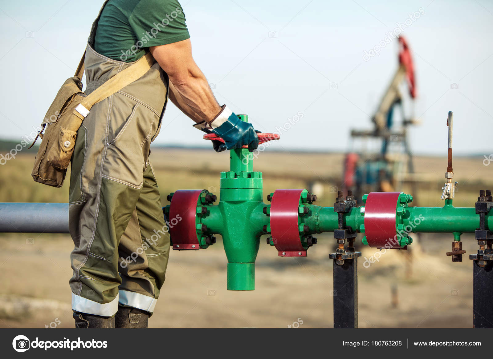 Oil worker is turning valve on the oil pipeline, oil deposit on the ...