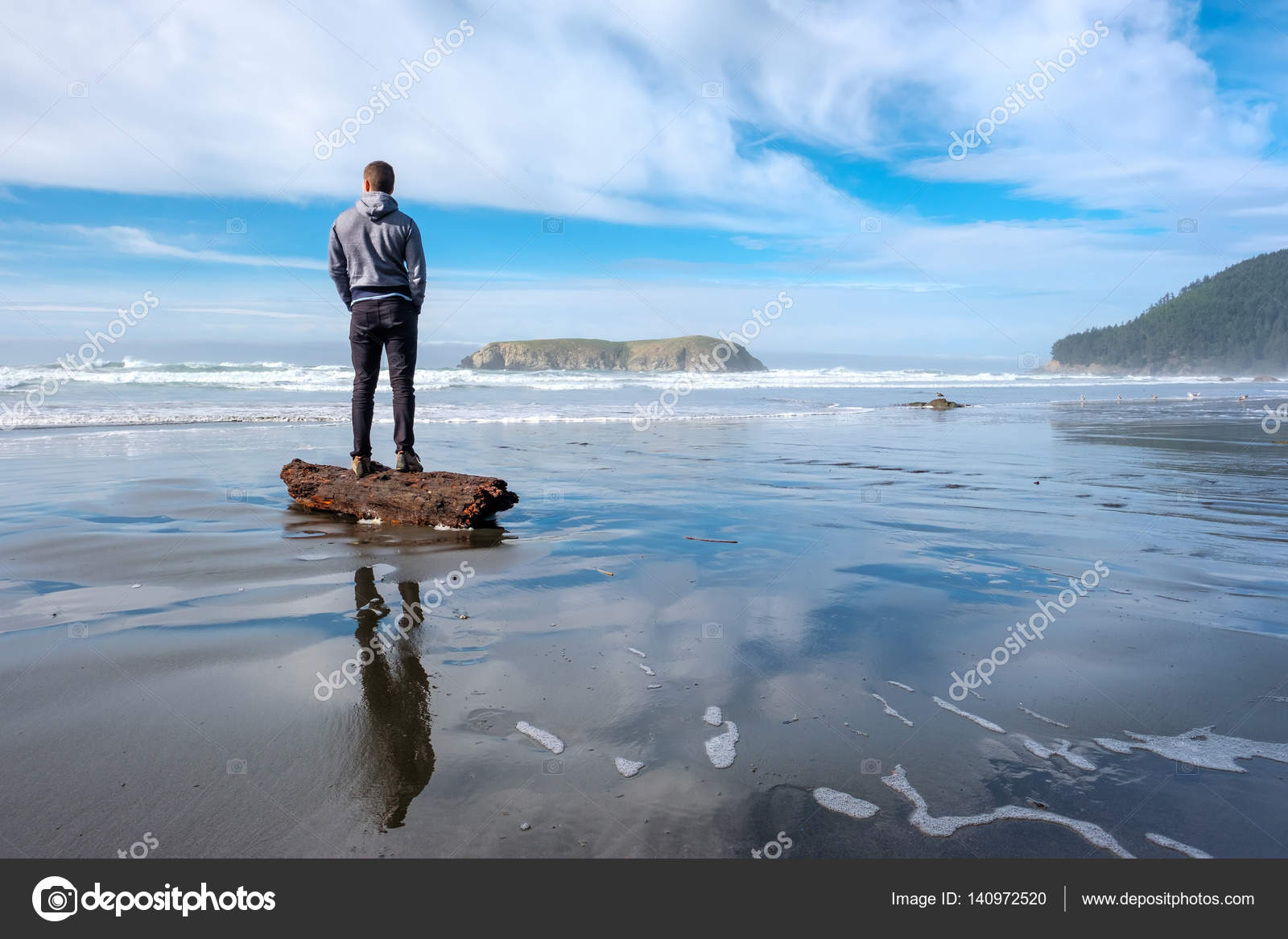 Man standing on log at beach Stock Photo by ©haveseen 140972520