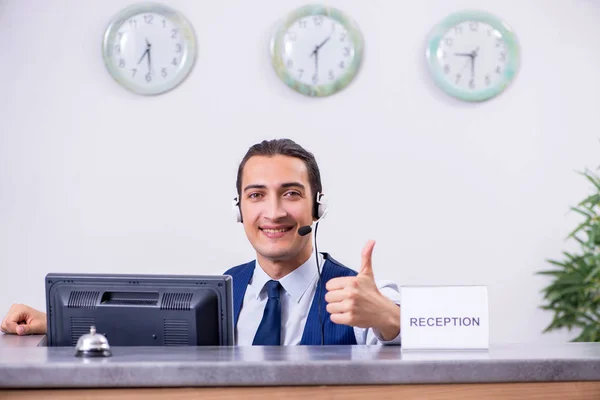 Young man receptionist at the hotel counter - Stock Image - Everypixel