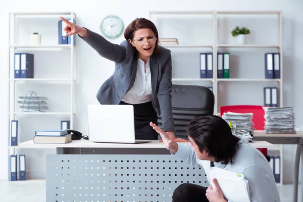 Old female boss and young male employee in the office - Stock Image ...