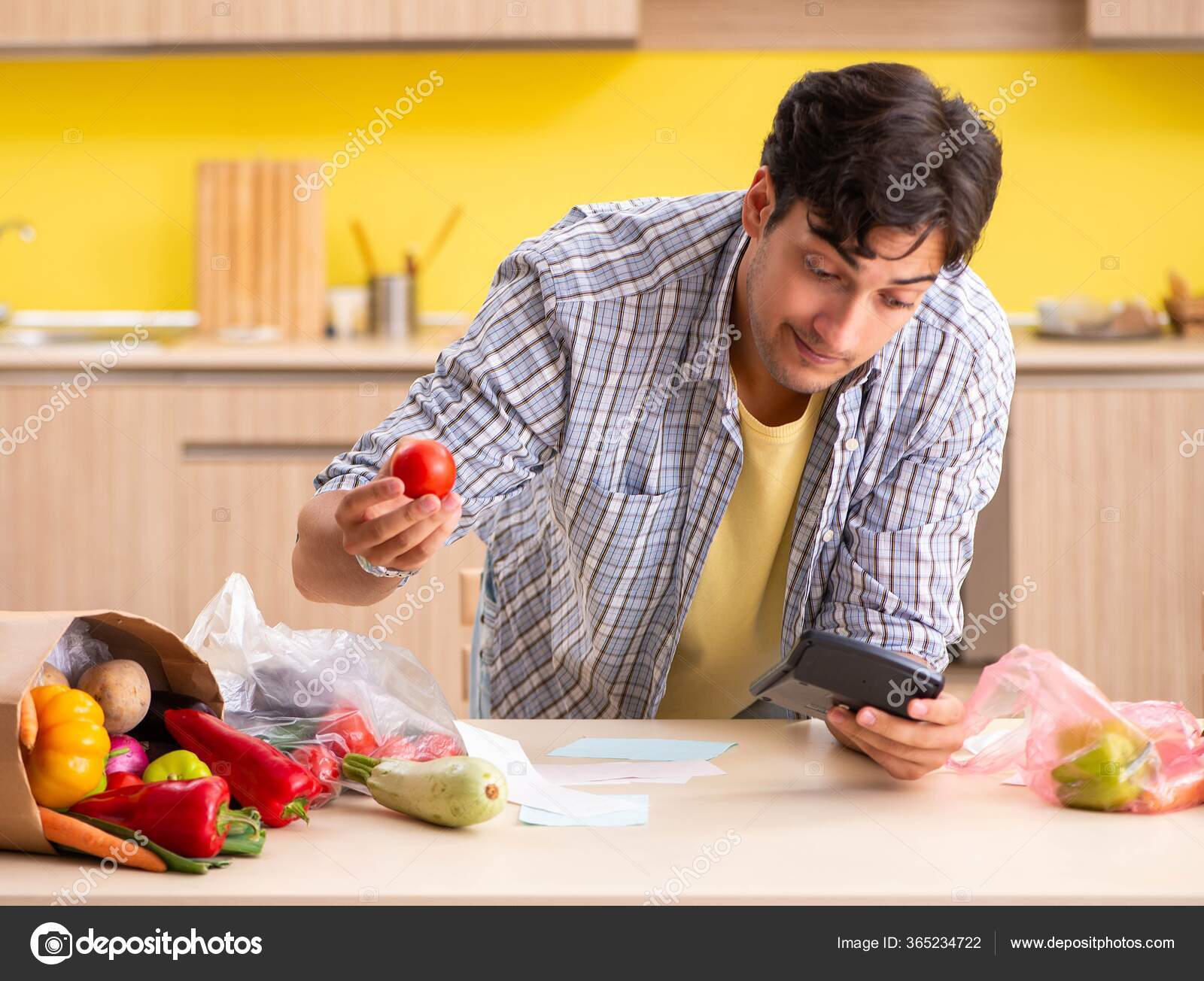 Young man calculating expences for vegetables in kitchen Stock Photo by ...