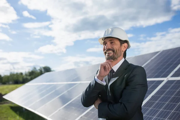 Man in business suit happily smailing, solar panels on backstage ...