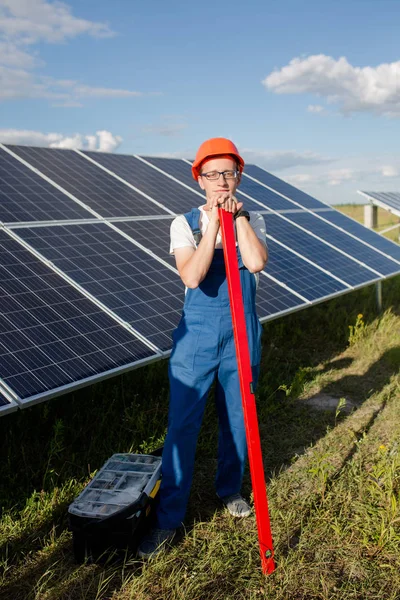 Young worker standing at solar energy station in the field. Stock Photo ...