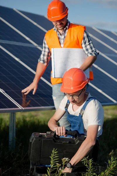 Young worker standing at solar energy station in the field. Stock Photo ...