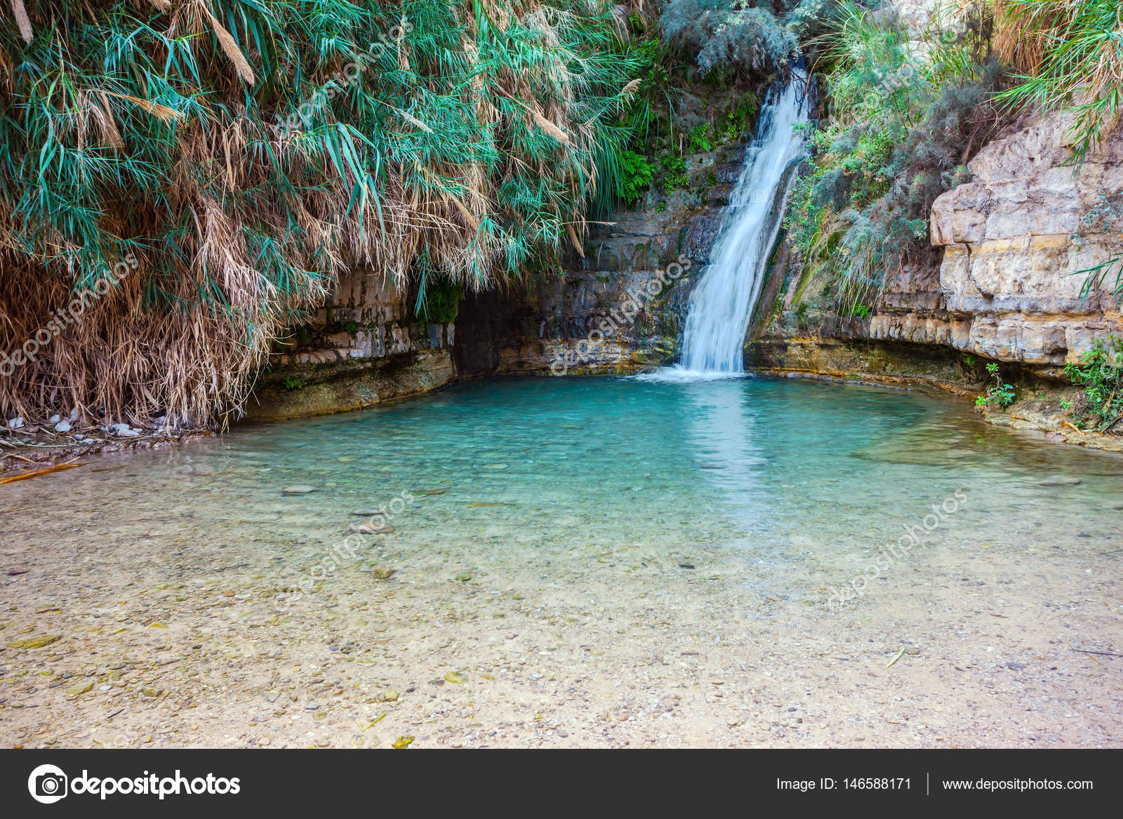 Waterfall flowing into clear shallow lake Stock Photo by ©kavramm 146588171
