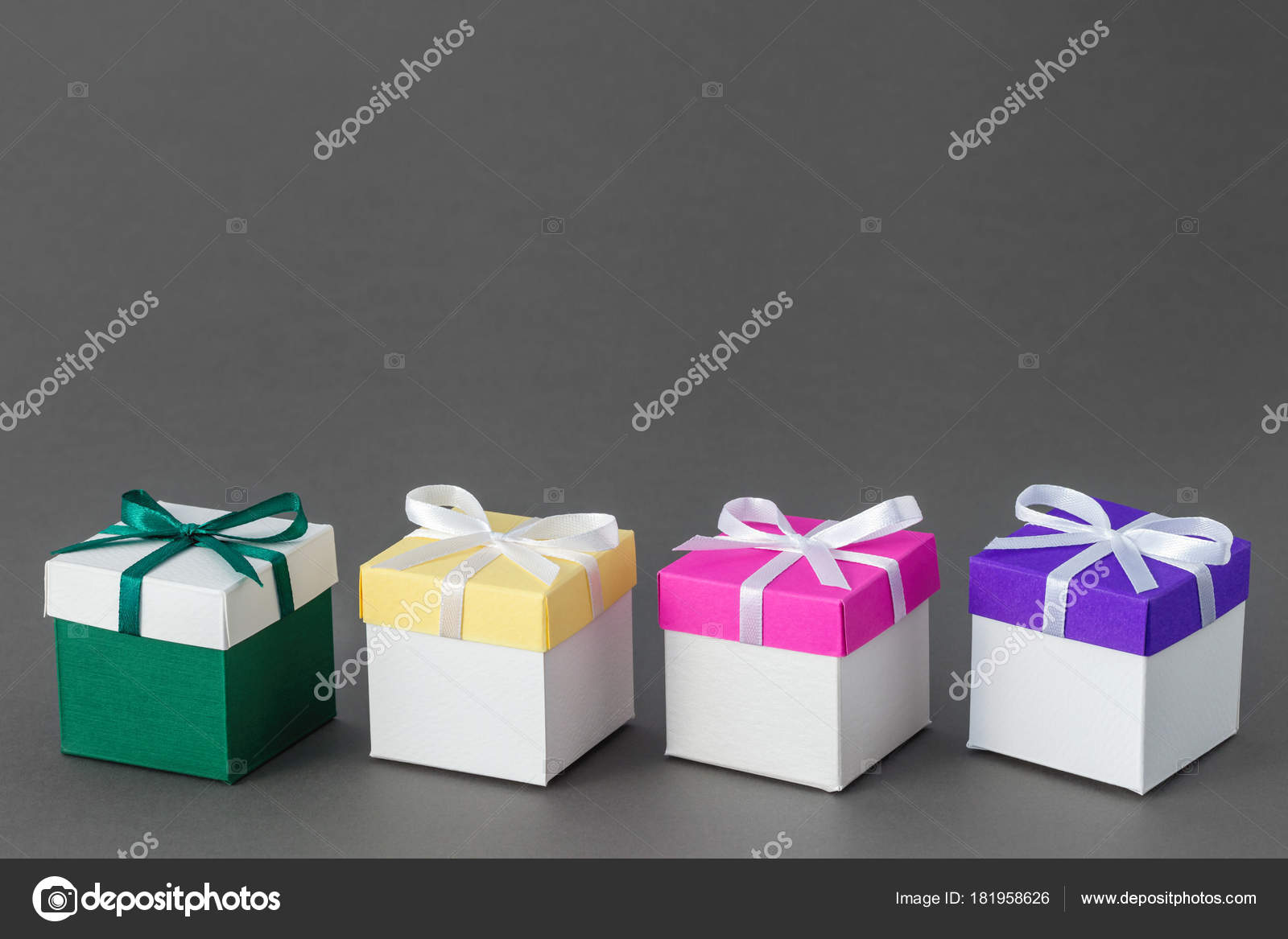 Four gift boxes with ribbons on gray background. Copy space for text ...