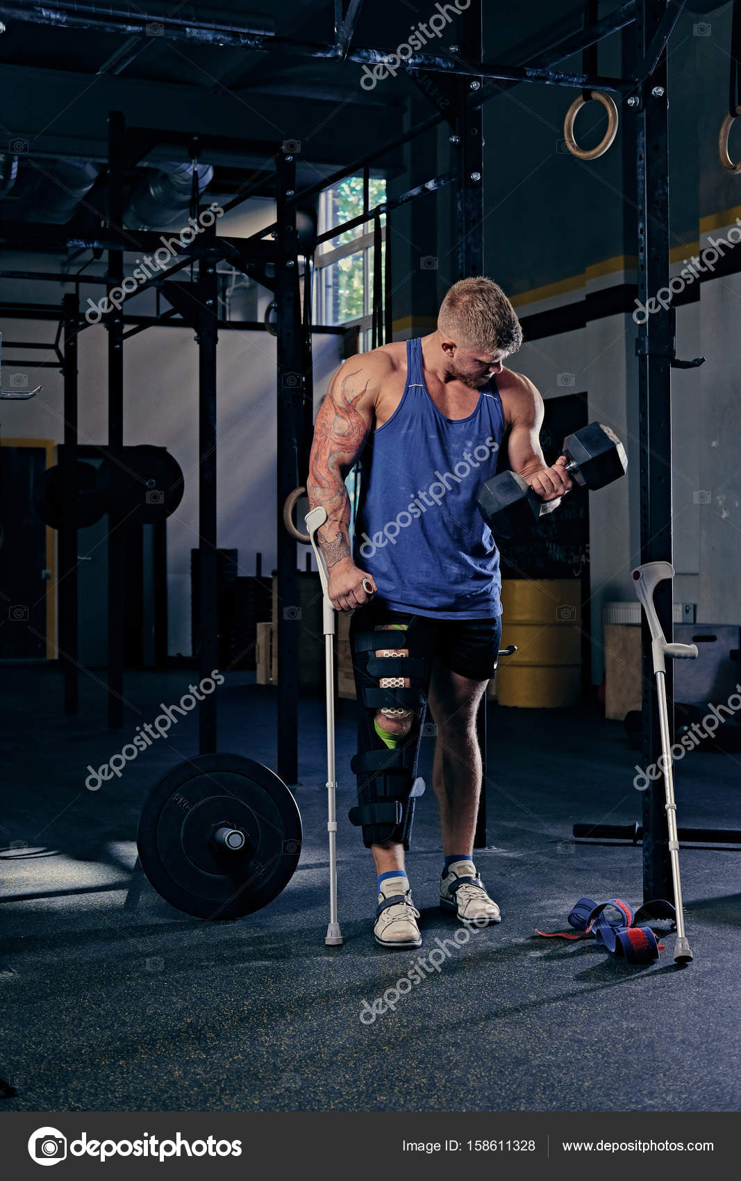 Bodybuilder on crutches holds dumbbell. Stock Photo by ©fxquadro 158611328