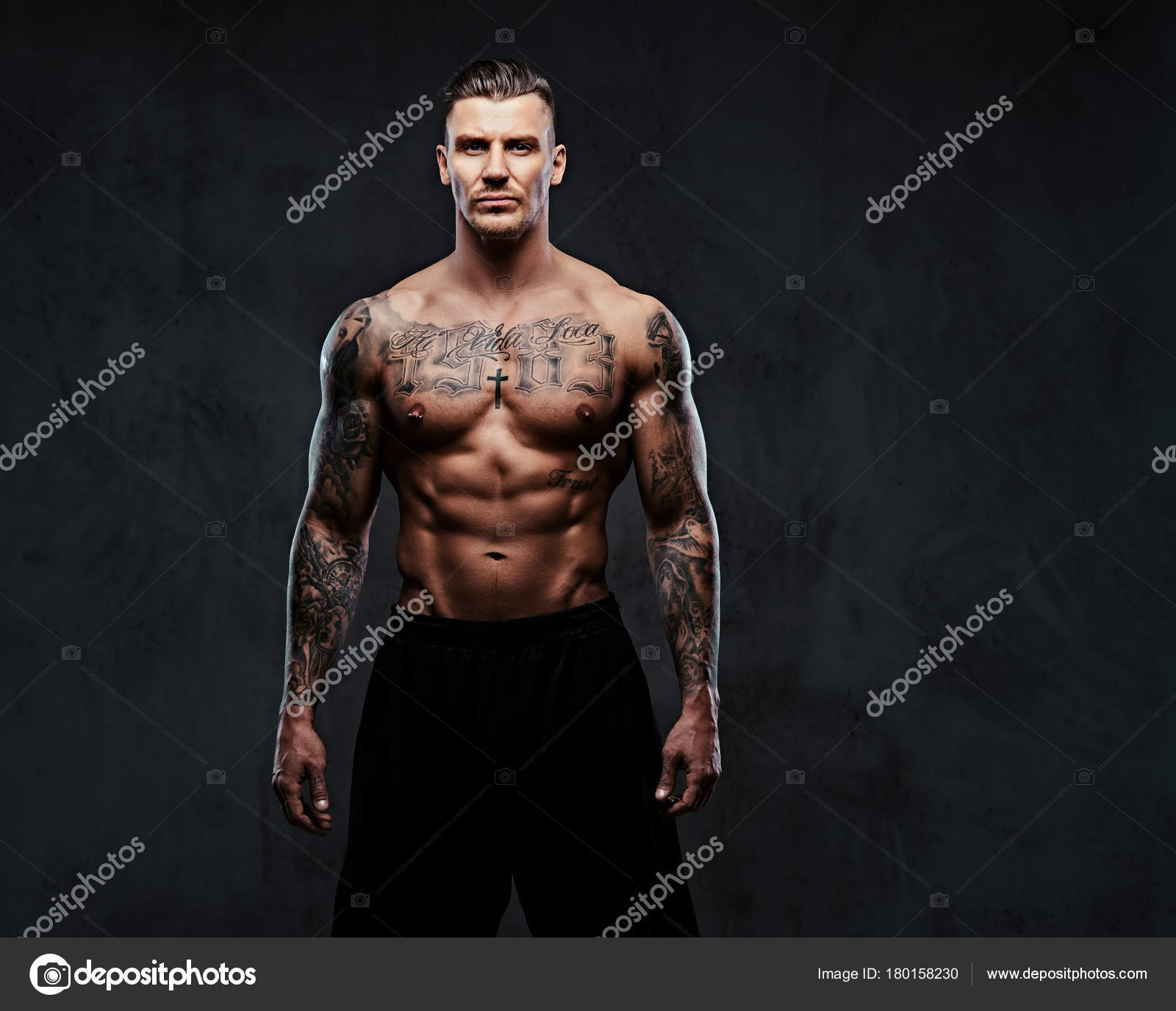A muscular tattooed man on a dark background. — Stock Photo © fxquadro ...