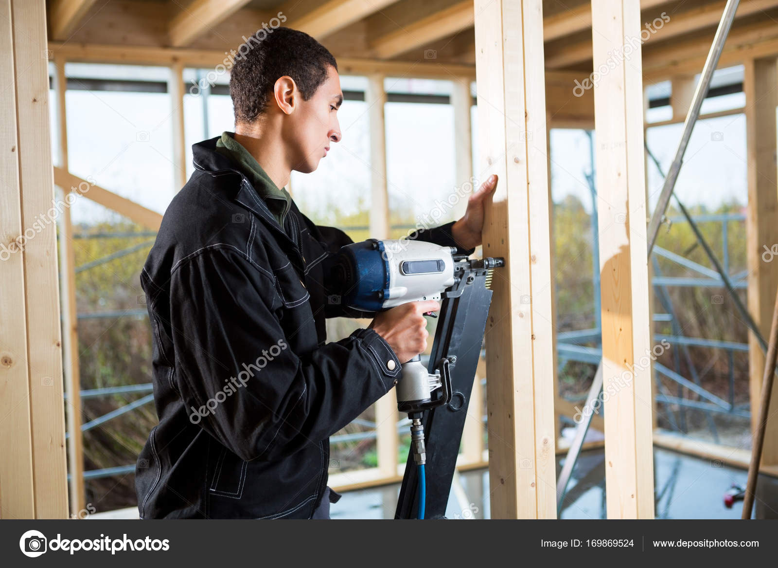 Side View Of Male Carpenter Drilling Wood At Site Stock Photo by ...