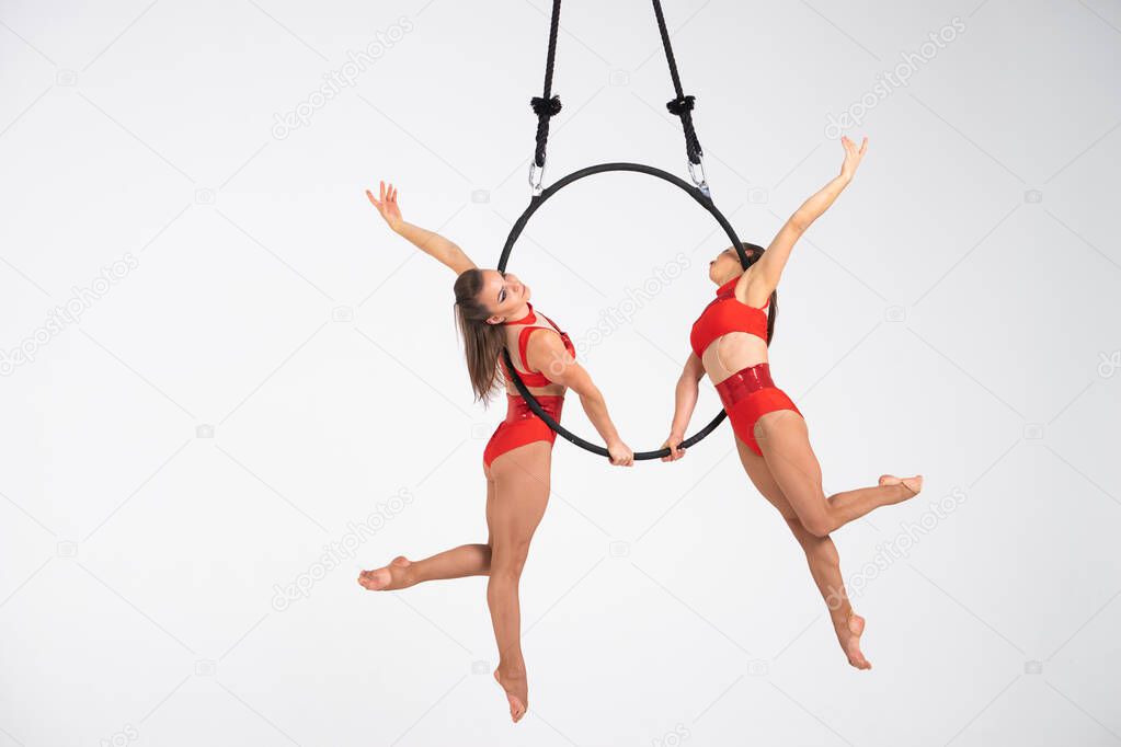 Gemelos dúo de circo femenino en el aro aéreo aislado en blanco 2024