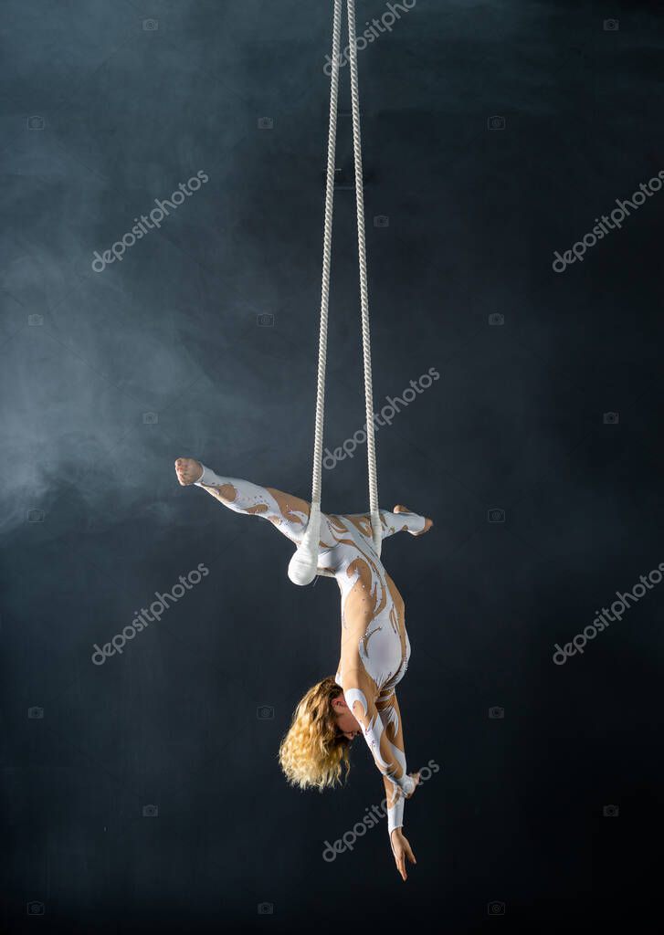 Una joven realiza los elementos acrobáticos en el trapecio de aire ...