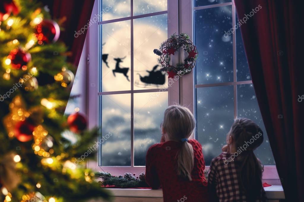 Girls sitting by window and looking at Santa — Stock Photo ...