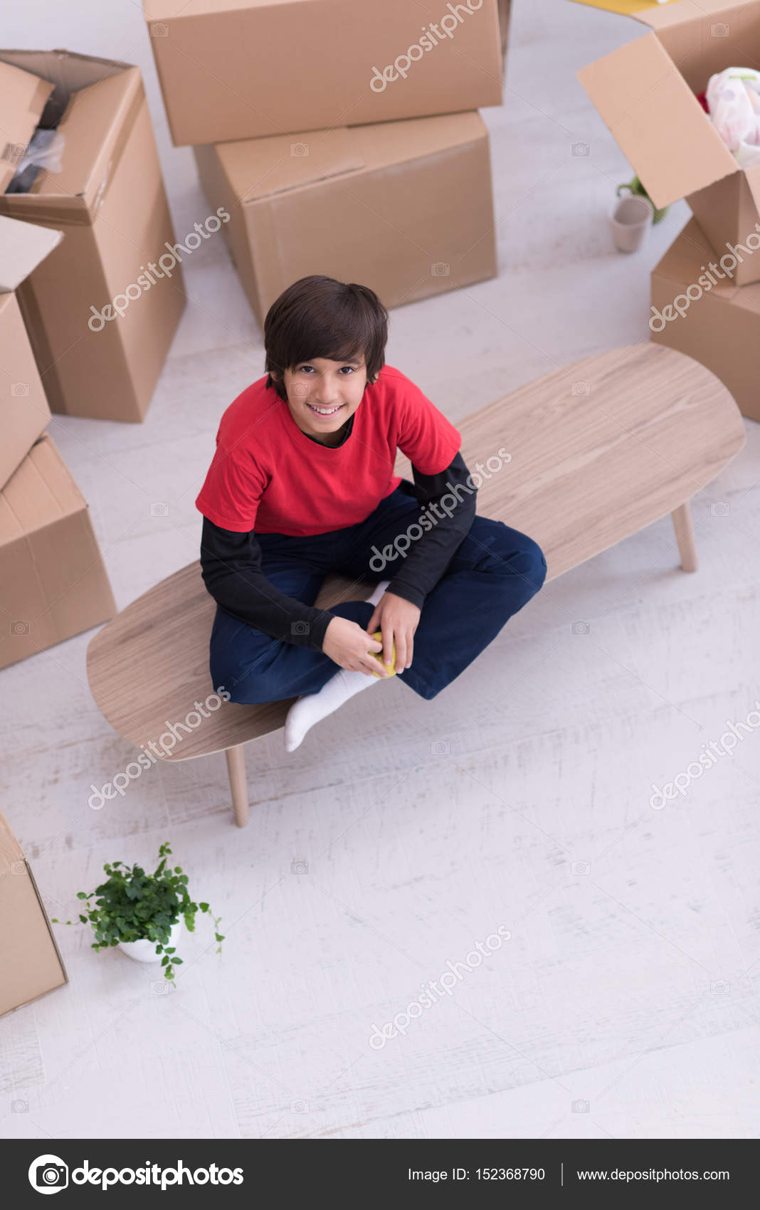 Boy sitting on the table with cardboard boxes around him top vie Stock ...