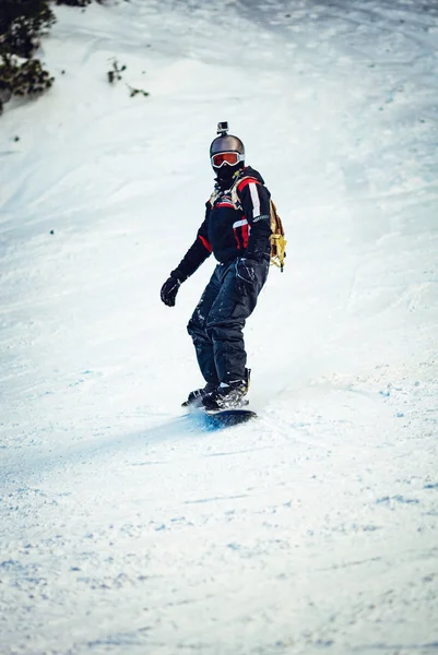 Young man rides snowboard and enjoying a winter day on mountain slopes ...