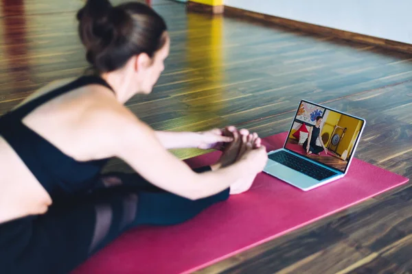 Young woman following yoga classes at a distance on a laptop. - Stock ...