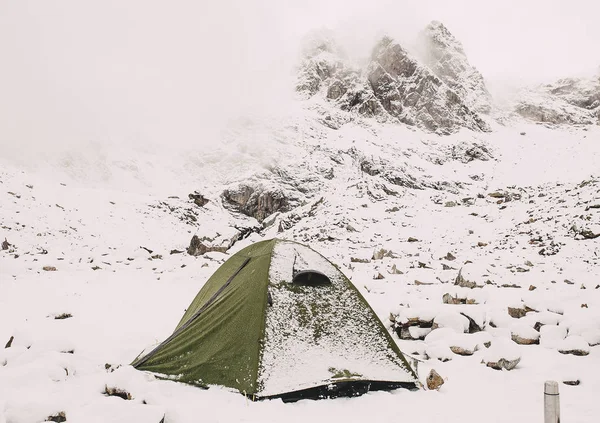 A bright snow survival shelter tent in a snow blizzard in the mountains ...