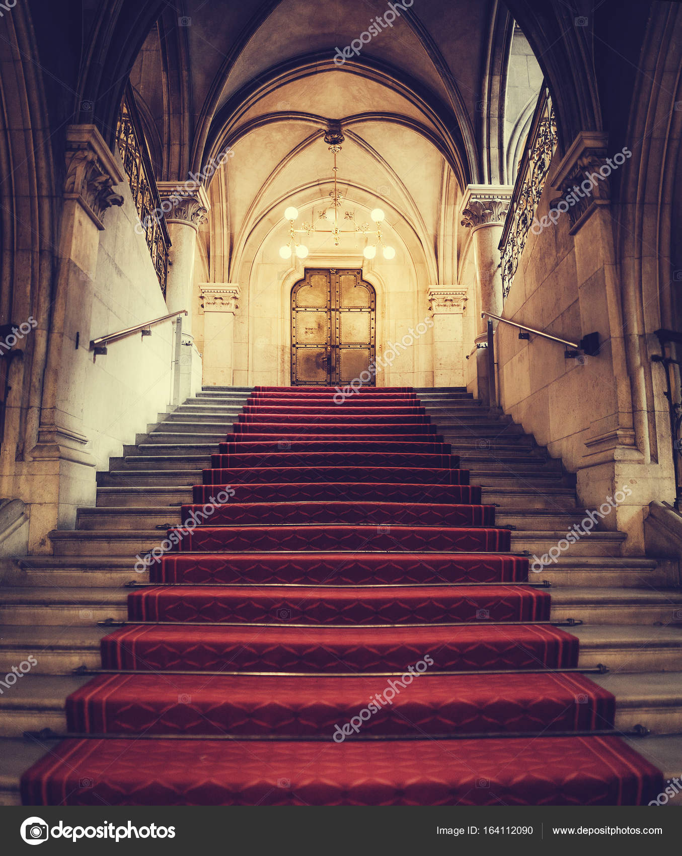 Beautiful antique staircase with a red carpet and door in castle or ...