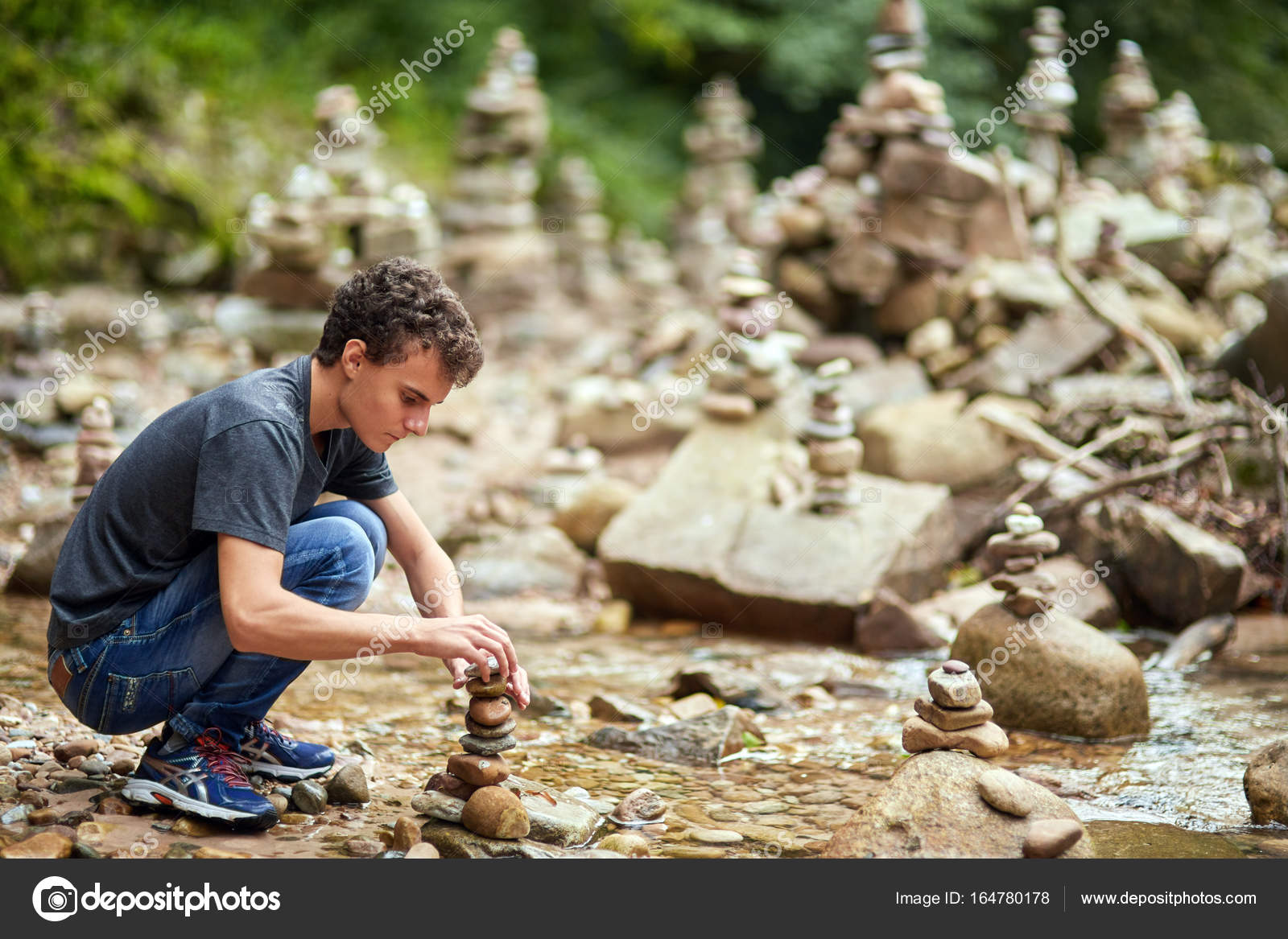 Boy making towers of stones Stock Photo by ©Xalanx 164780178