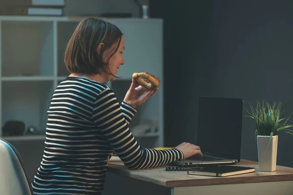 Business woman eating baked snack over office laptop computer - Stock ...