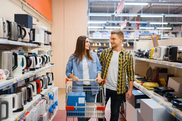 Young couple with cart in electronics store. Man and woman buying home ...