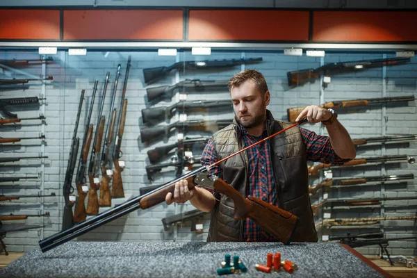 Man cleans rifle barrel at counter in gun shop. Euqipment for hunters ...