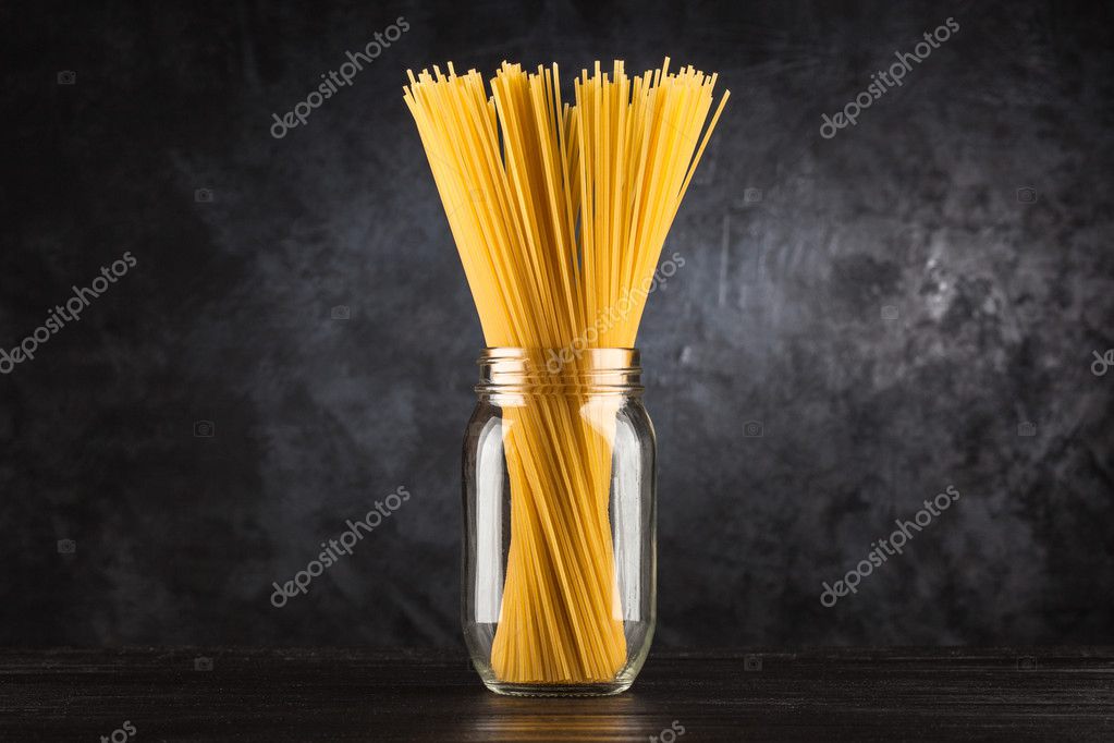 Raw spaghetti on dark background Stock Photo by ©gdolgikh 125031466