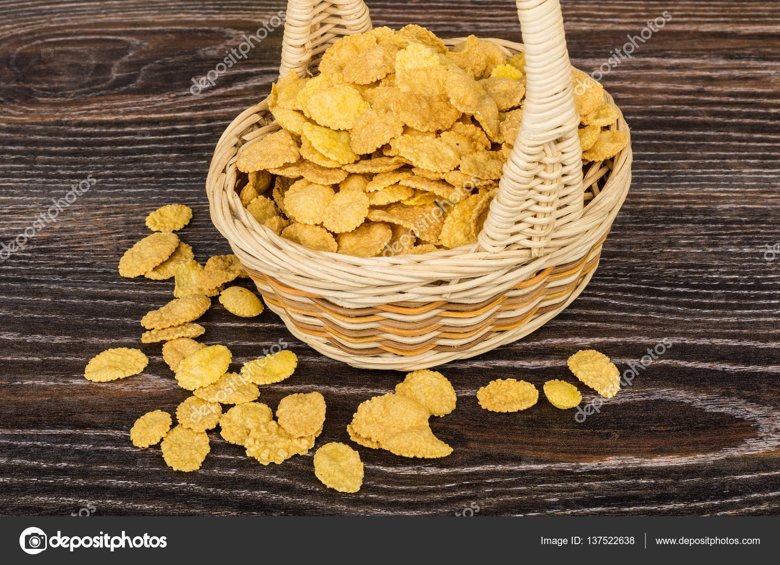 Corn flakes in wicker basket and scattered flakes on table — Stock ...
