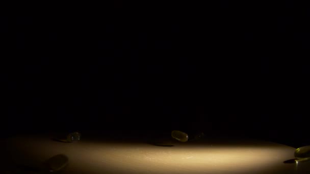 Pill capsule falling and spilling on black surface in slow motion ...