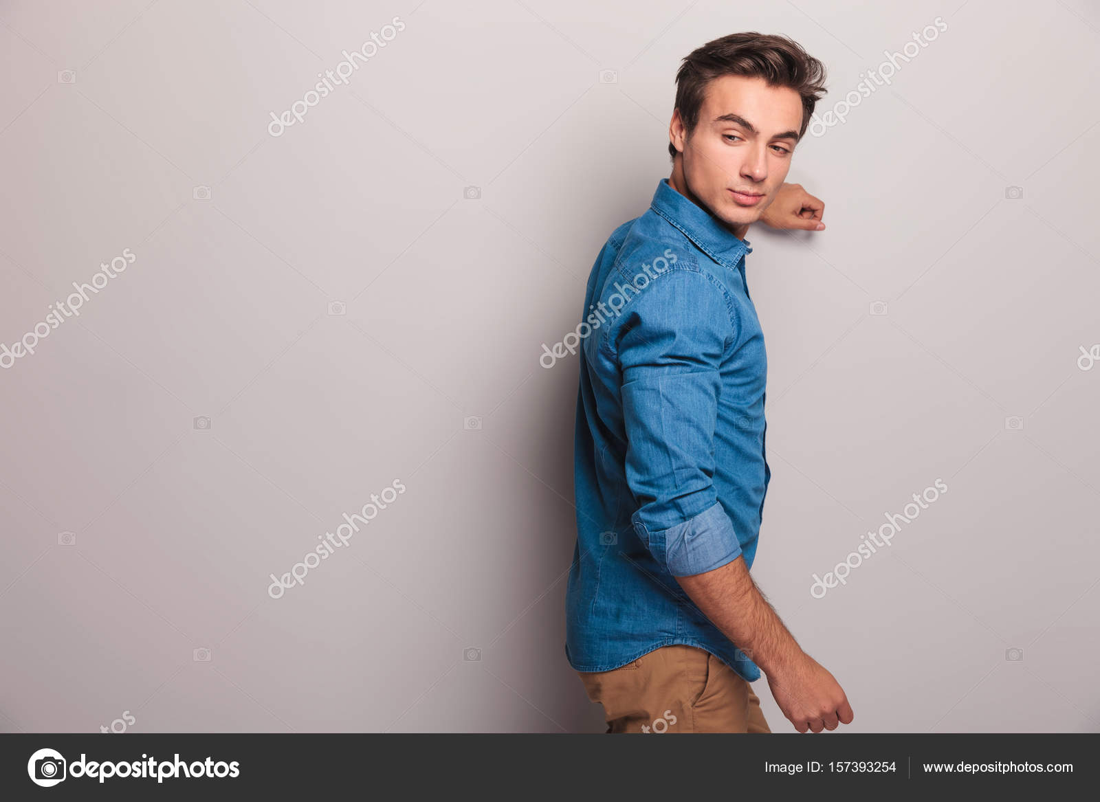 Man leaning on grey wall looks back over his shoulder ⬇ Stock Photo ...