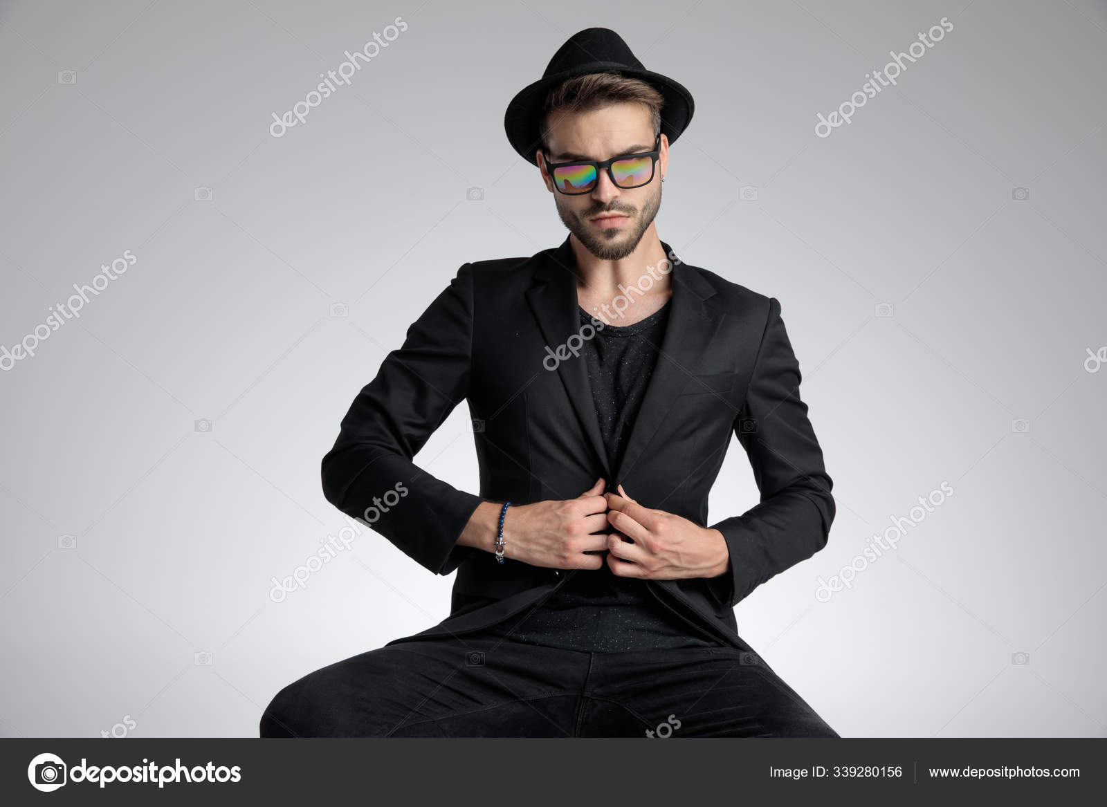 Sexy cool guy arranging coat and sitting in a fashion pose — Stock ...
