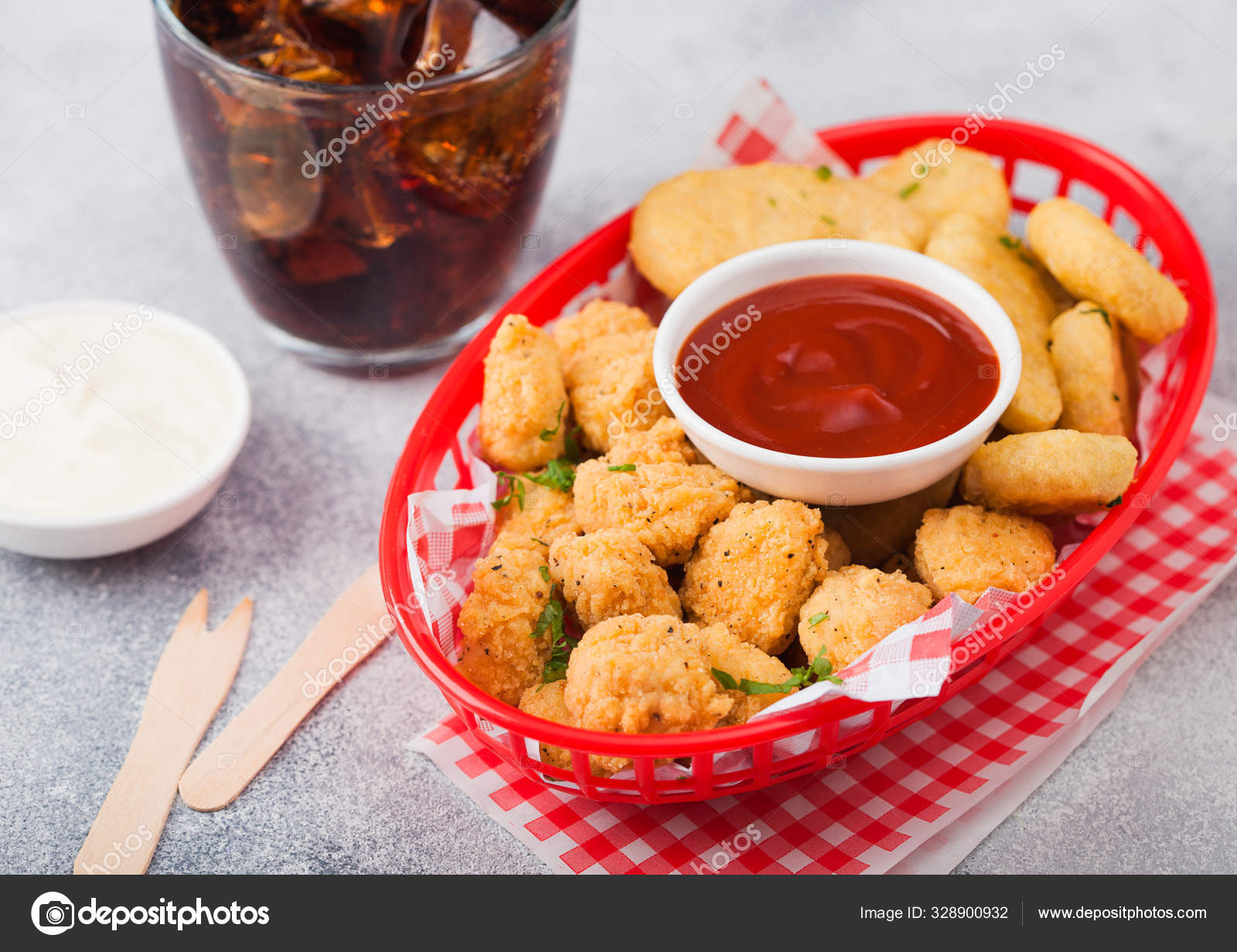 Buttered chicken nuggets and popcorn bites in red fast food basket with ...