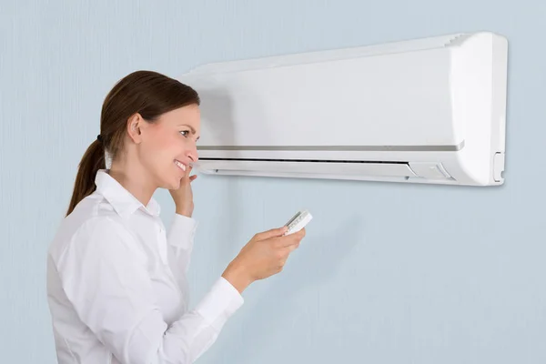 Woman using air conditioner Stock Photo by ©AndreyPopov 142432979