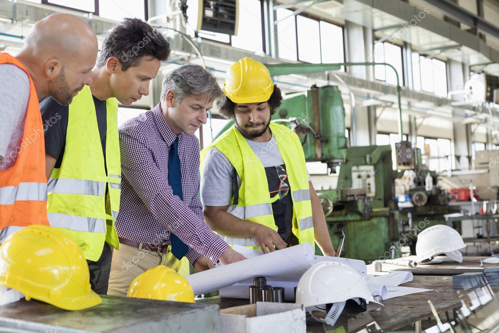 Supervisor with workers discussing over blueprints — Stock Photo ...