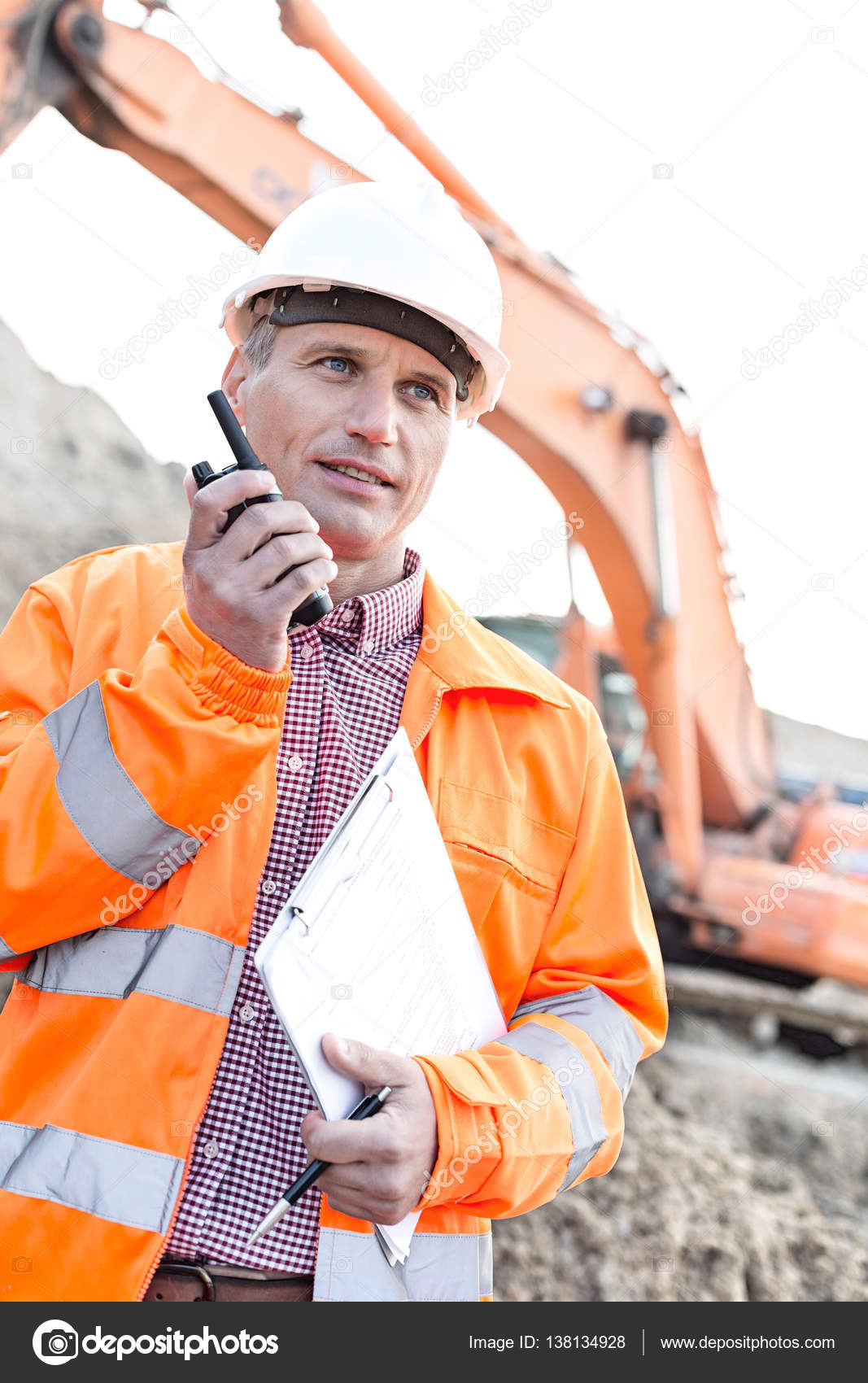 Supervisor holding clipboard while using walkie-talkie Stock Photo by ...