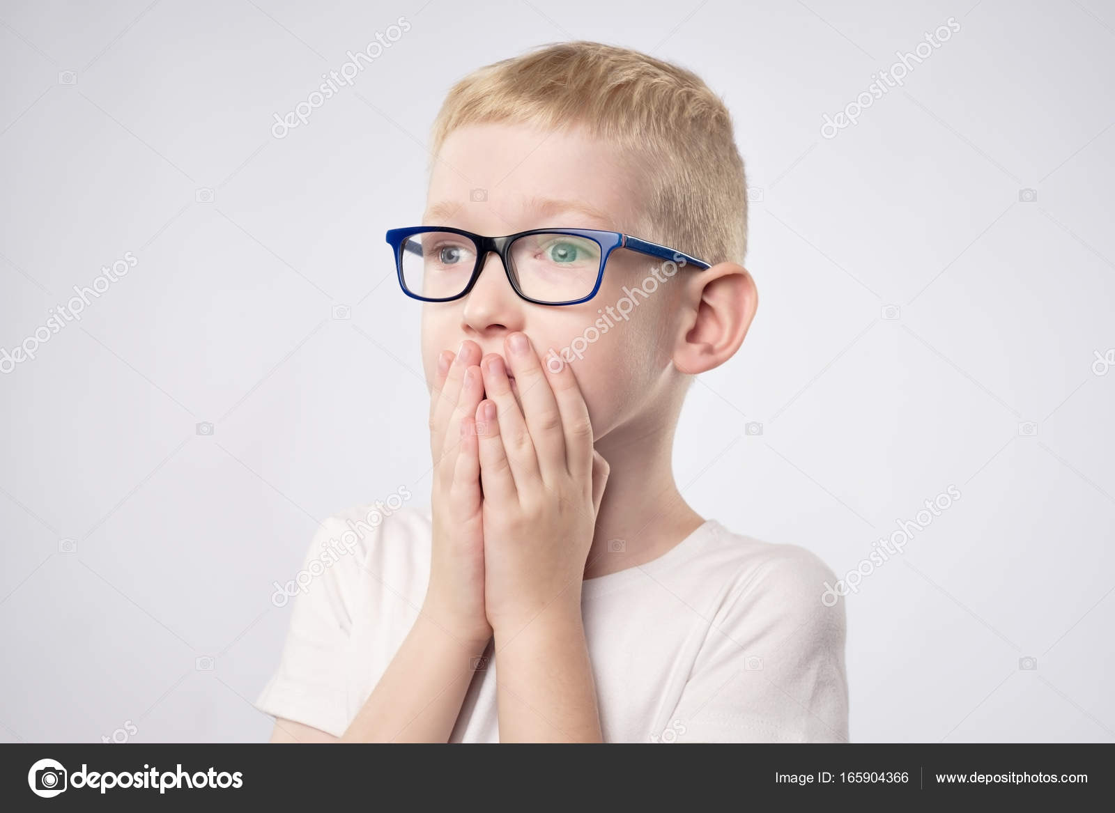 Scared litle kid boy with blond hair holding hands on face because he ...