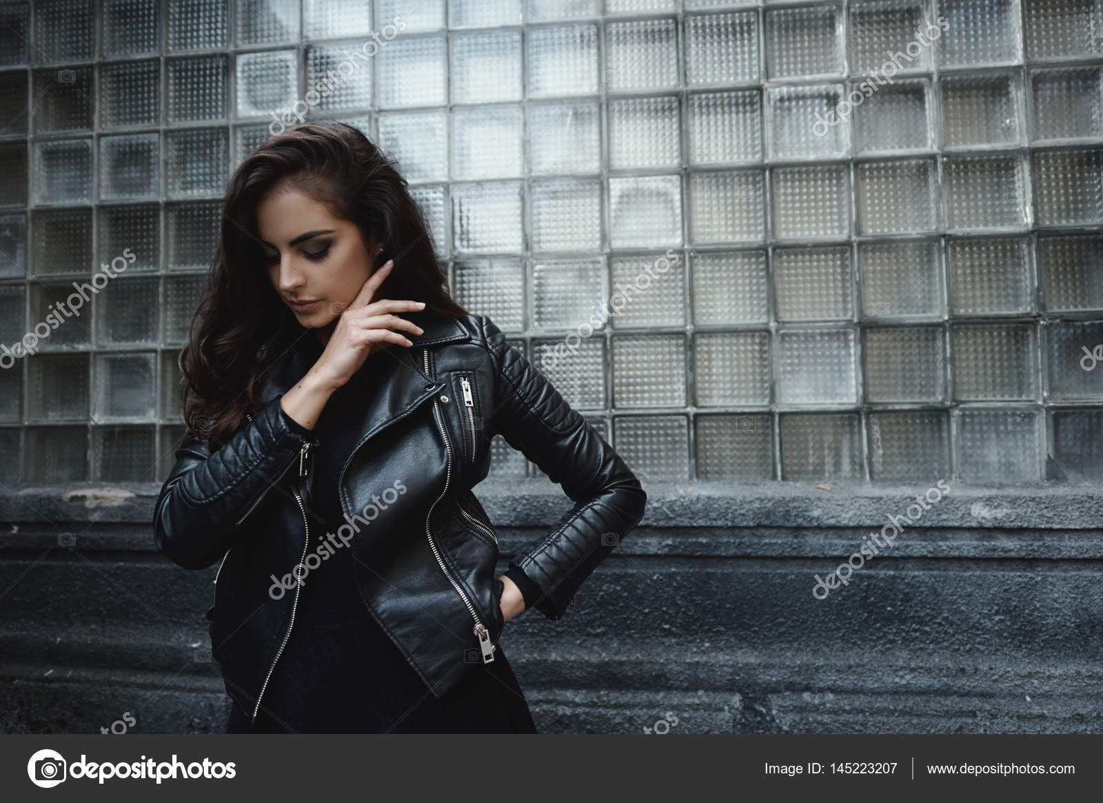 Eastern beautiful woman wearing biker jacket poses in backyard of ...