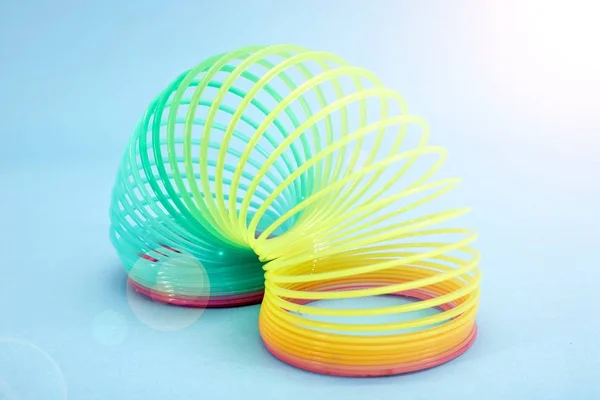 Rainbow colored plastic, slinky toy on the wooden table. 3D rend Stock ...